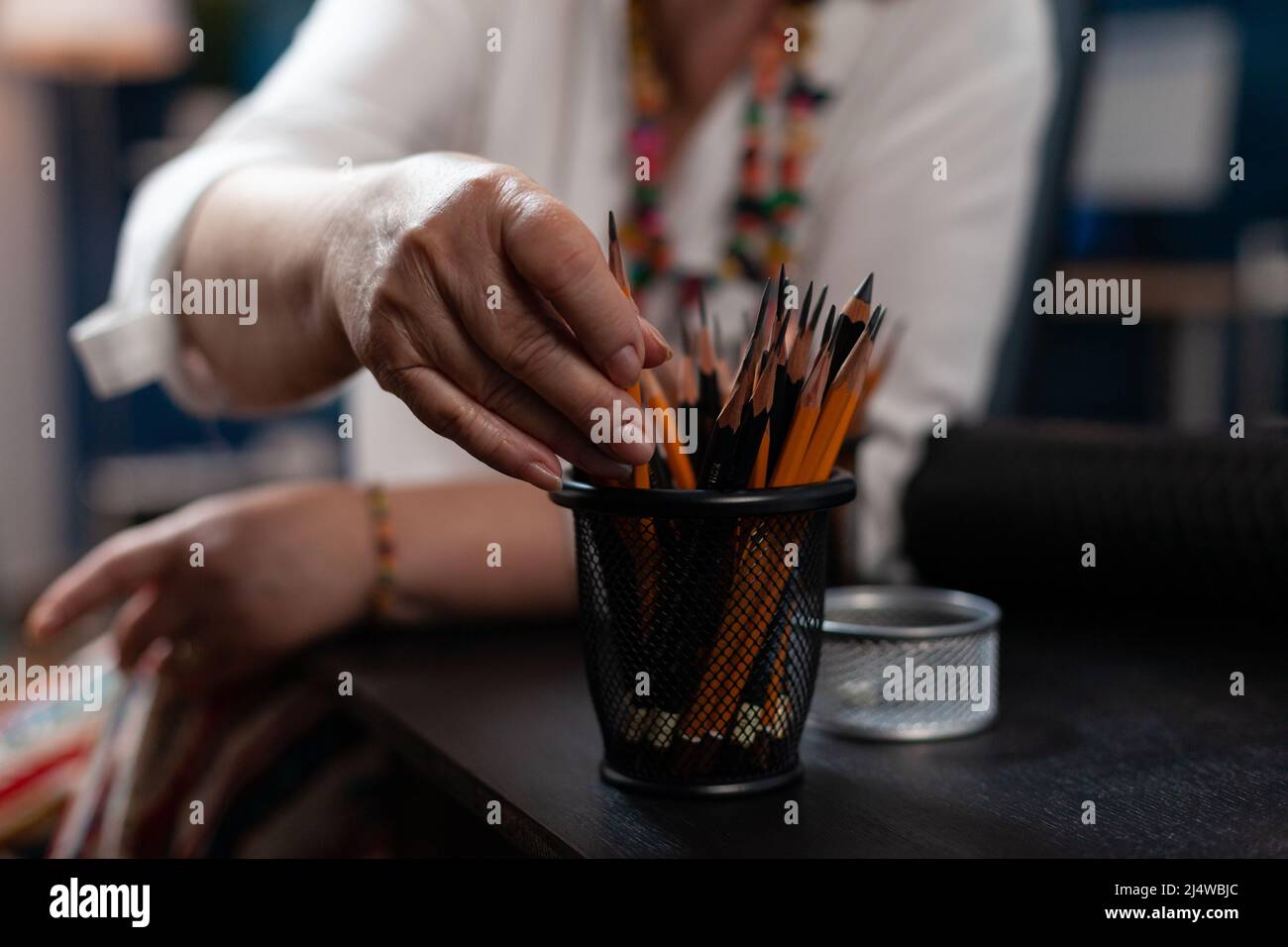 Closeup of elderly woman retired artist hand picking a pencil for ...