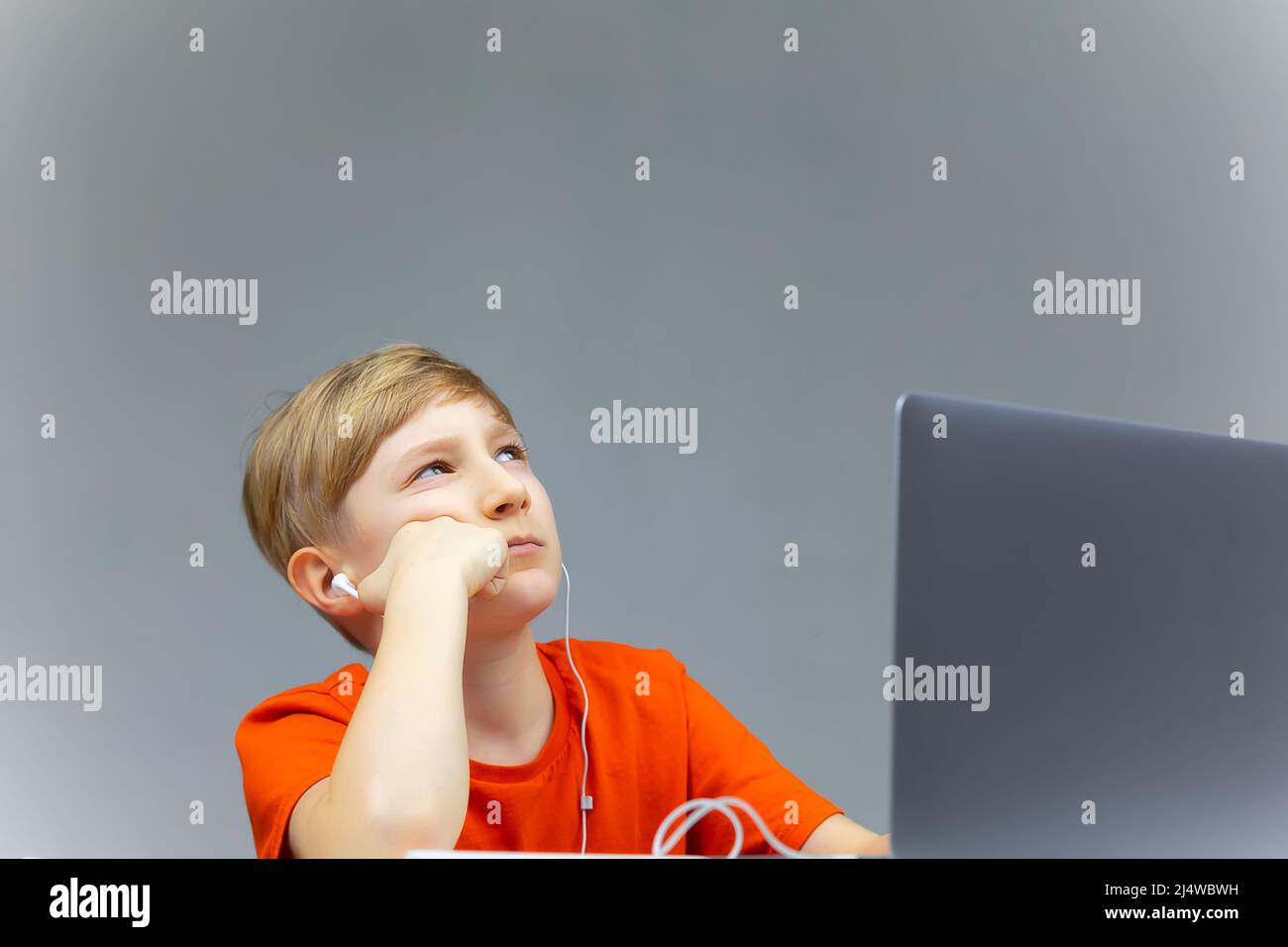 a boy sitting at a laptop thinking and looking up Stock Photo - Alamy