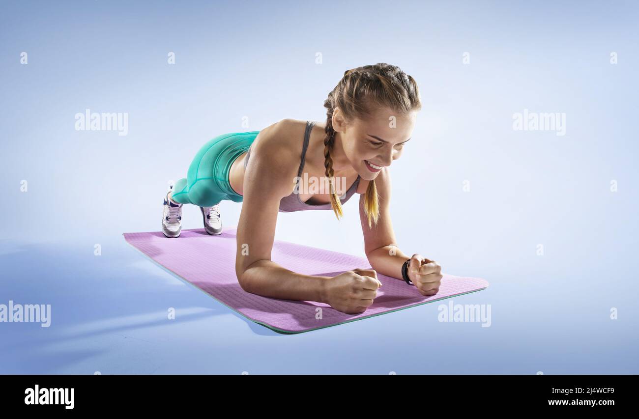 Sport. Muscular woman on a plank position use fitness gum. Muscular and ...