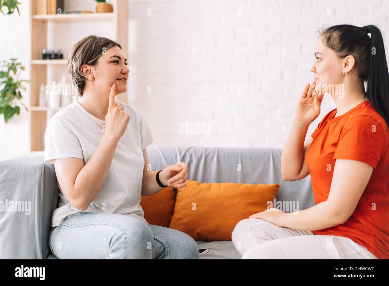 The teacher teaches the girl sign language while sitting on the couch ...
