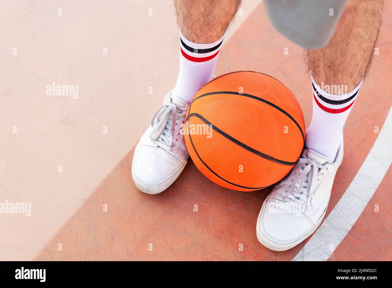 close up of a ball held between a man's feet on a basketball court ...