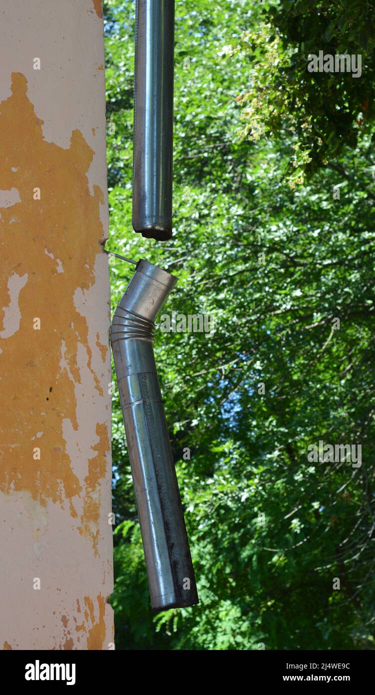Repairing, fixing a broken metal downspout, downpipe of an old house. A ...