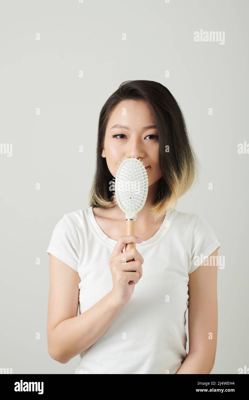 Portrait of smiling young woman with fresh hairut showing plastic brush ...