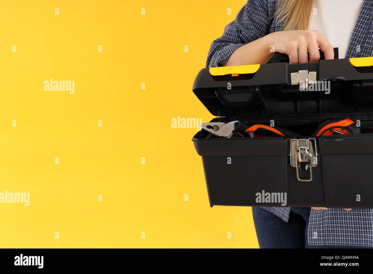 Concept of professions, young woman holds tools on yellow background ...
