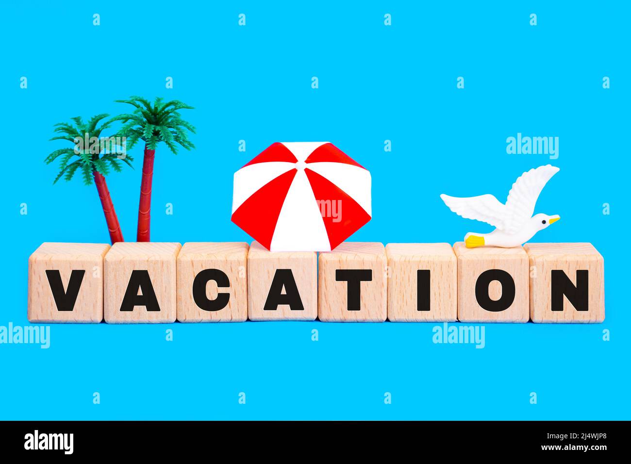 Word VACATION made from letter blocks, toy palm tree, sun umbrella and ...