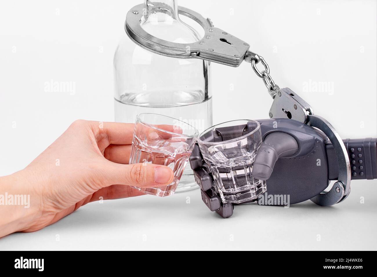 Mechanical and human hand with glasses and handcuffs on a white ...