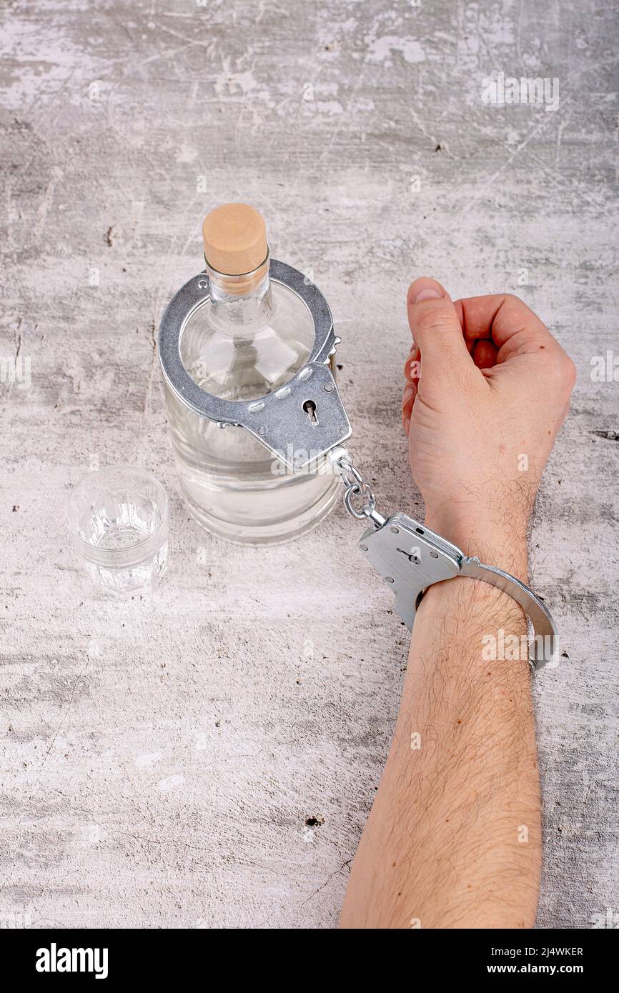 The concept of male alcohol addiction. A man's hand handcuffed to a ...