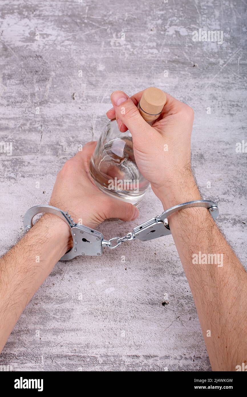 The concept of male alcohol addiction. Men's handcuffed hands are ...