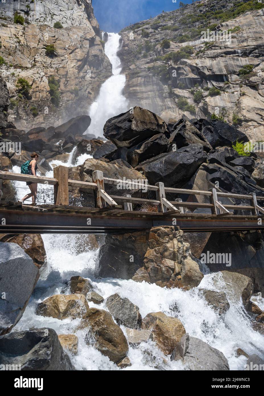 Hiker walking over the Wapama Falls bridge, in Yosemite National Park ...