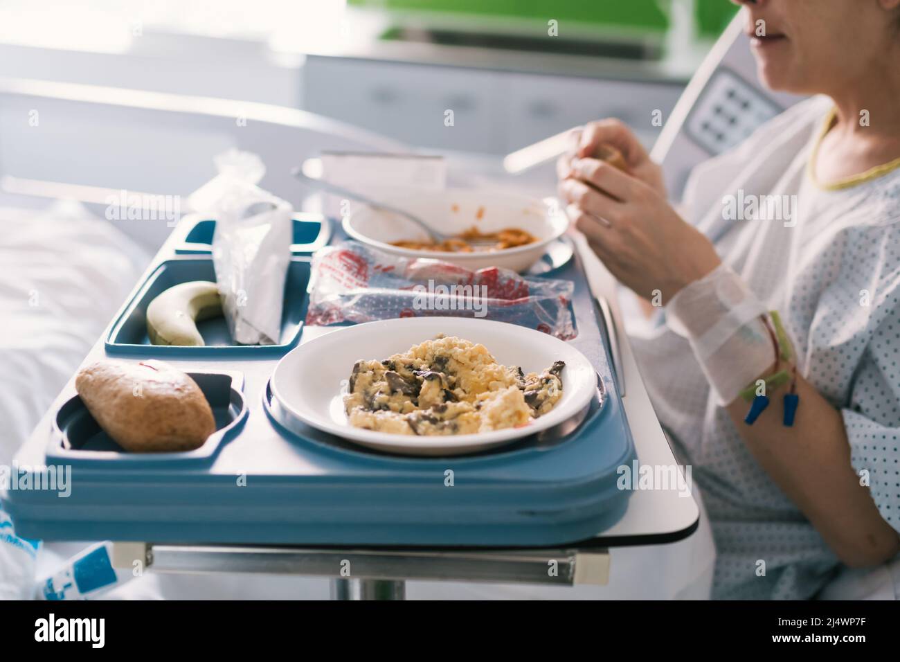 young woman who is hospitalized eating in the bed in the room the light ...
