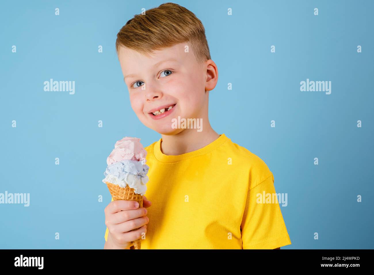 Positive boy holding ice cream on a blue background. Health benefits ...
