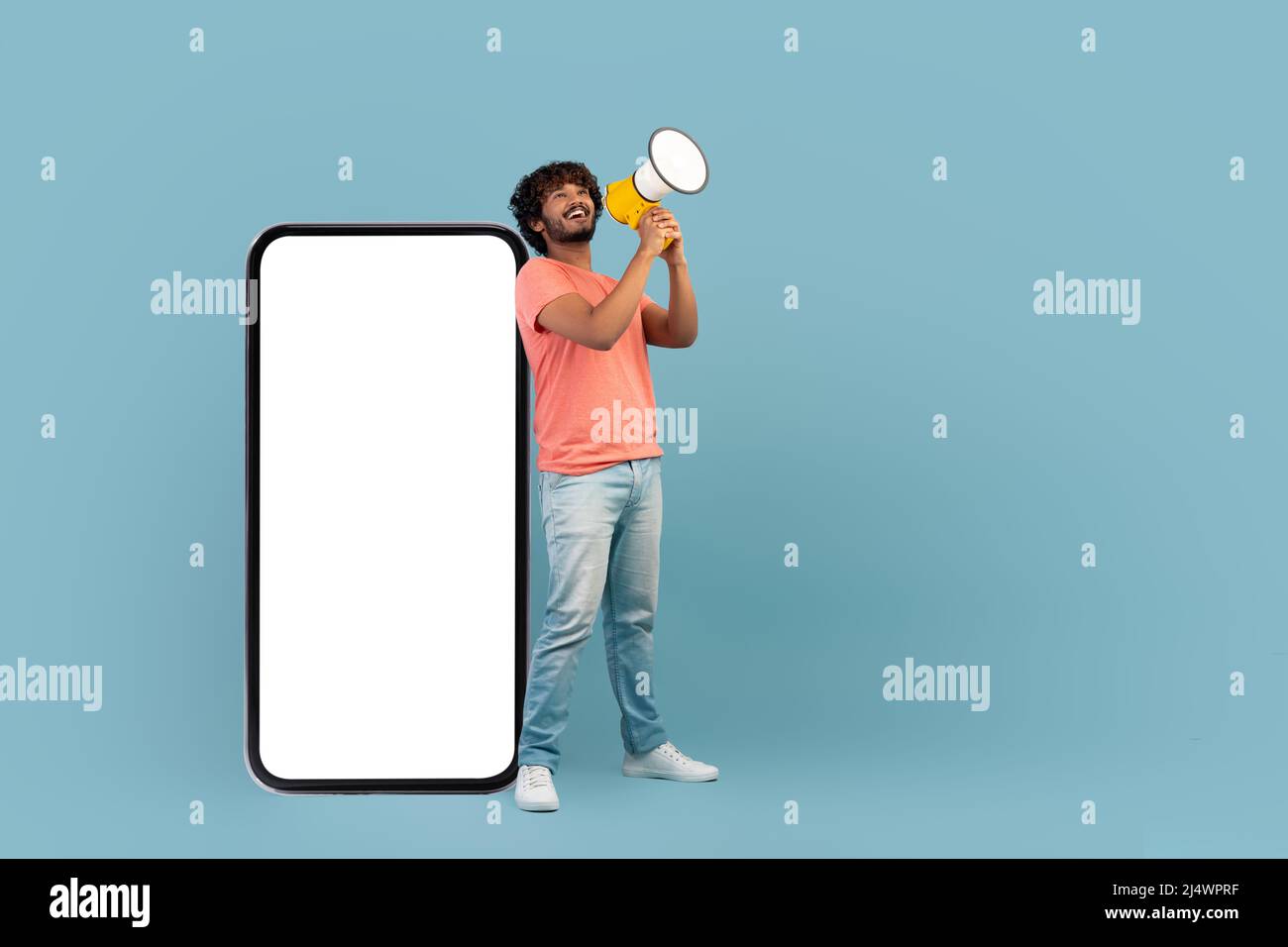 Positive indian guy with megaphone posing by smartphone, making ...