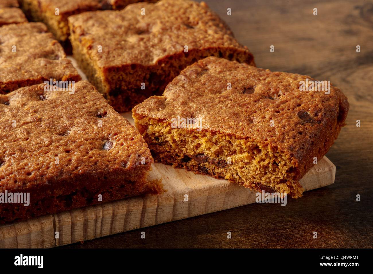 Blondie brownie dessert bars with chocolate chips, a close-up on a dark ...