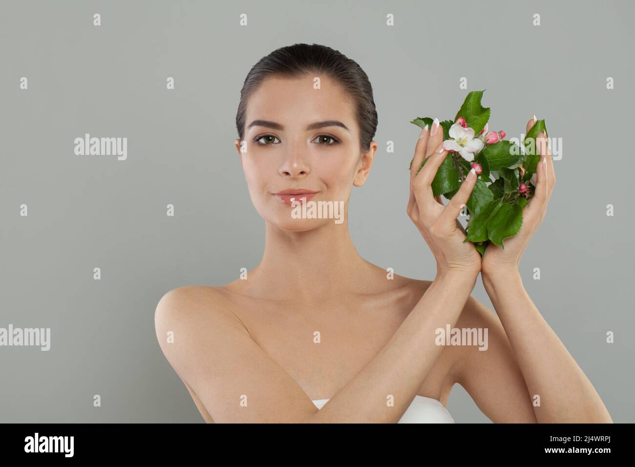 Beautiful young woman with clean fresh skin showing spring flowers ...