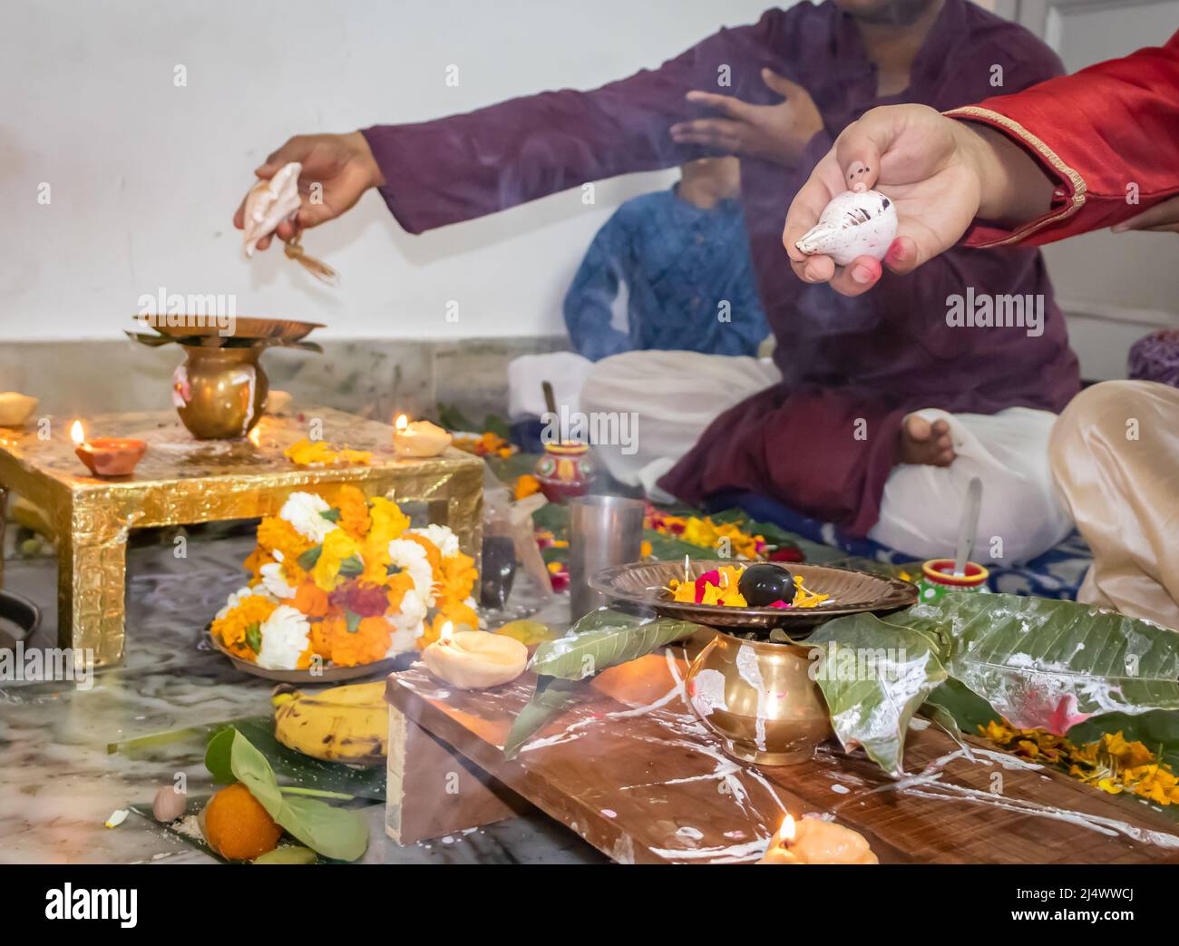 devotee doing religious ritual of holy god with conch shell and blurred ...