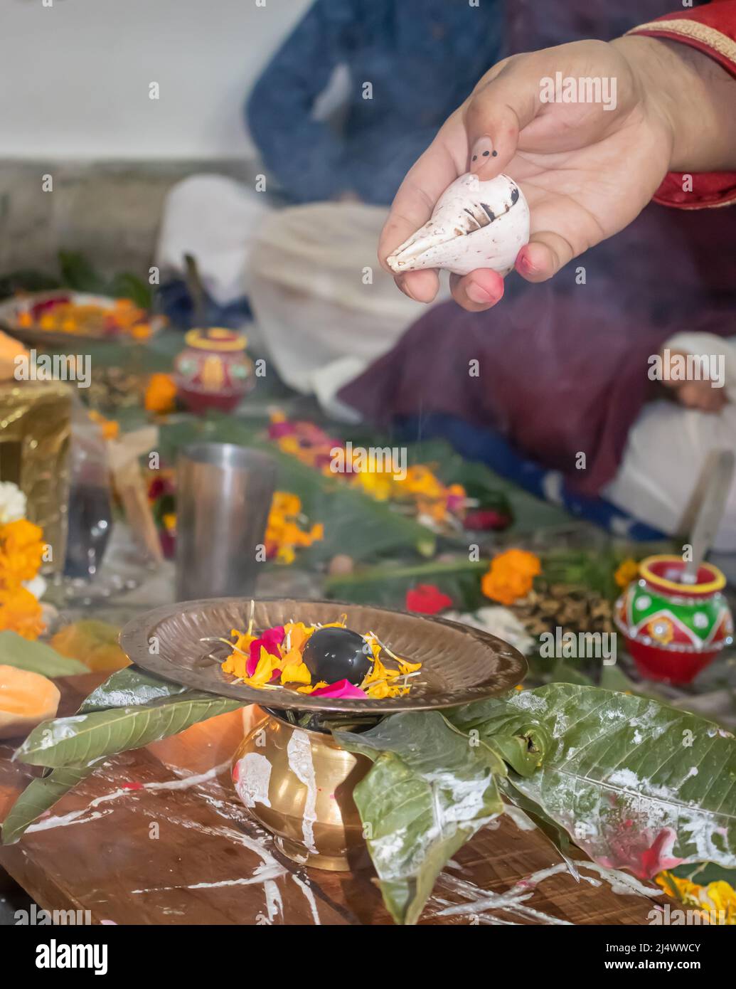 devotee doing religious ritual of holy god with conch shell and blurred ...