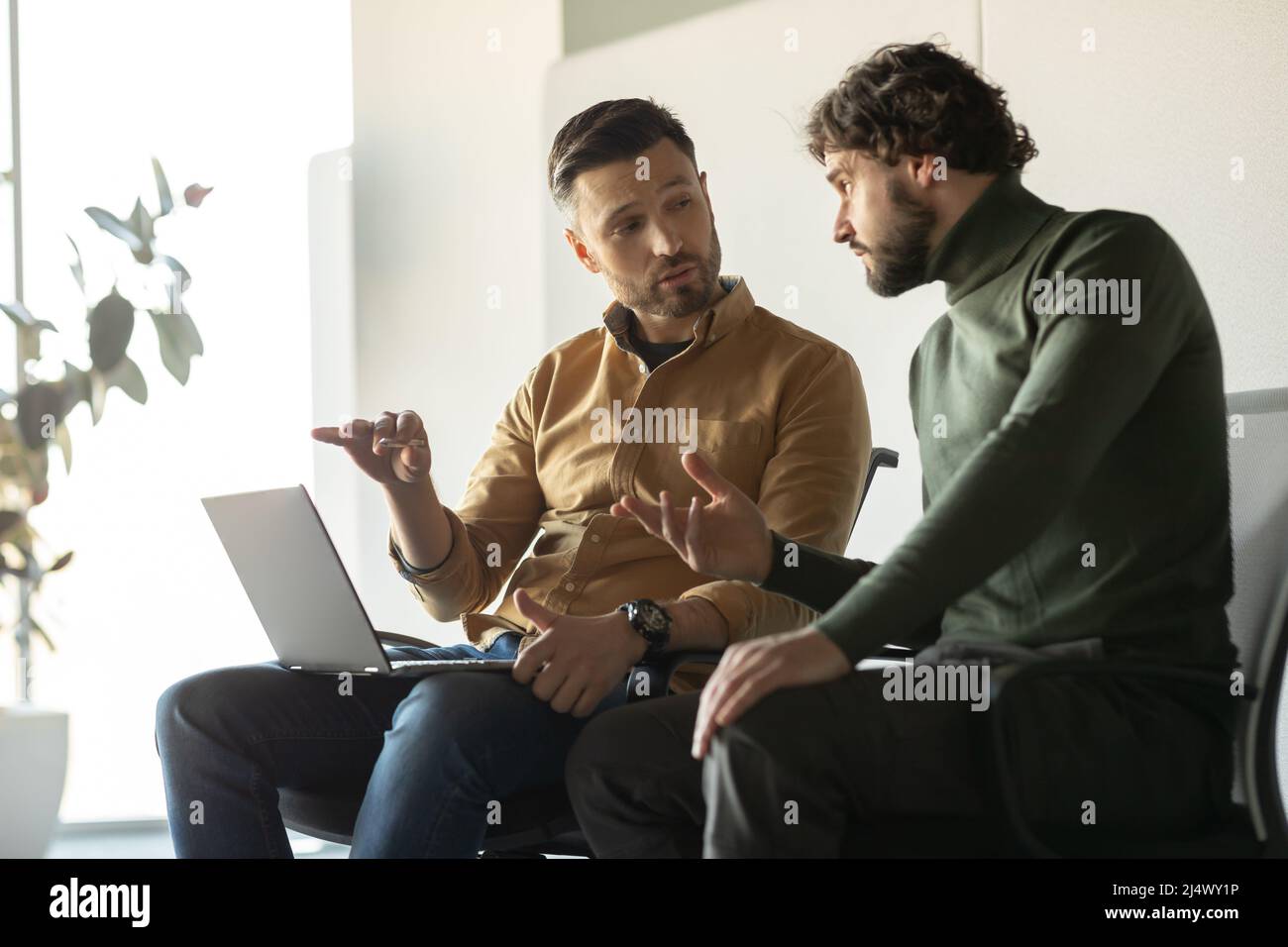 Portrait of two male colleagues discussing work projects and startup ...