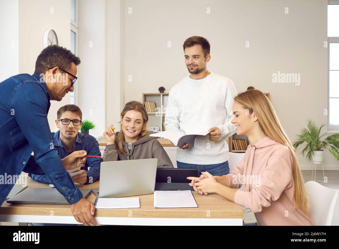 Smiling multiracial young people work together on computer Stock Photo ...