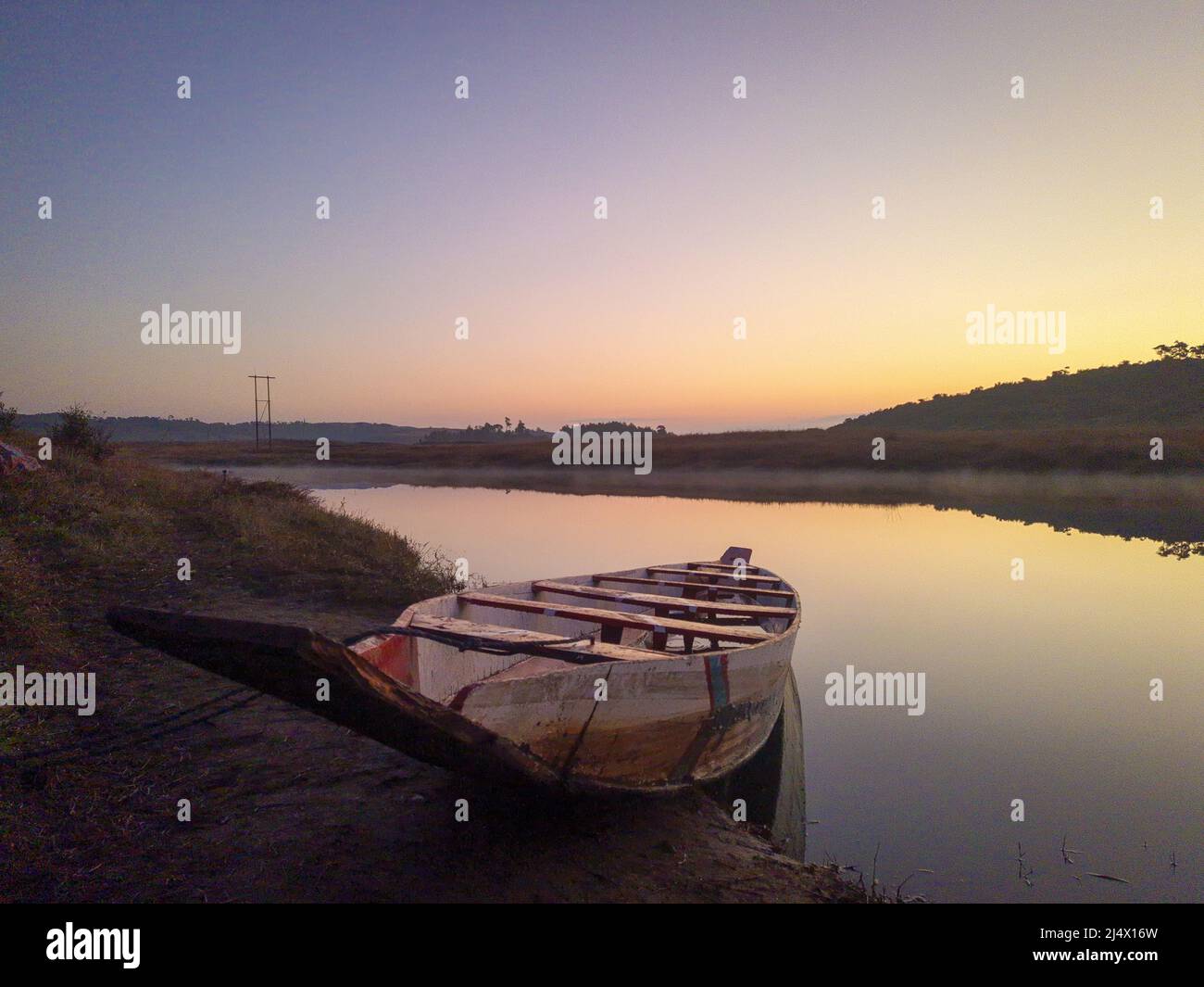 traditional wood boat at calm lake with dramatic sunrise colorful sky ...