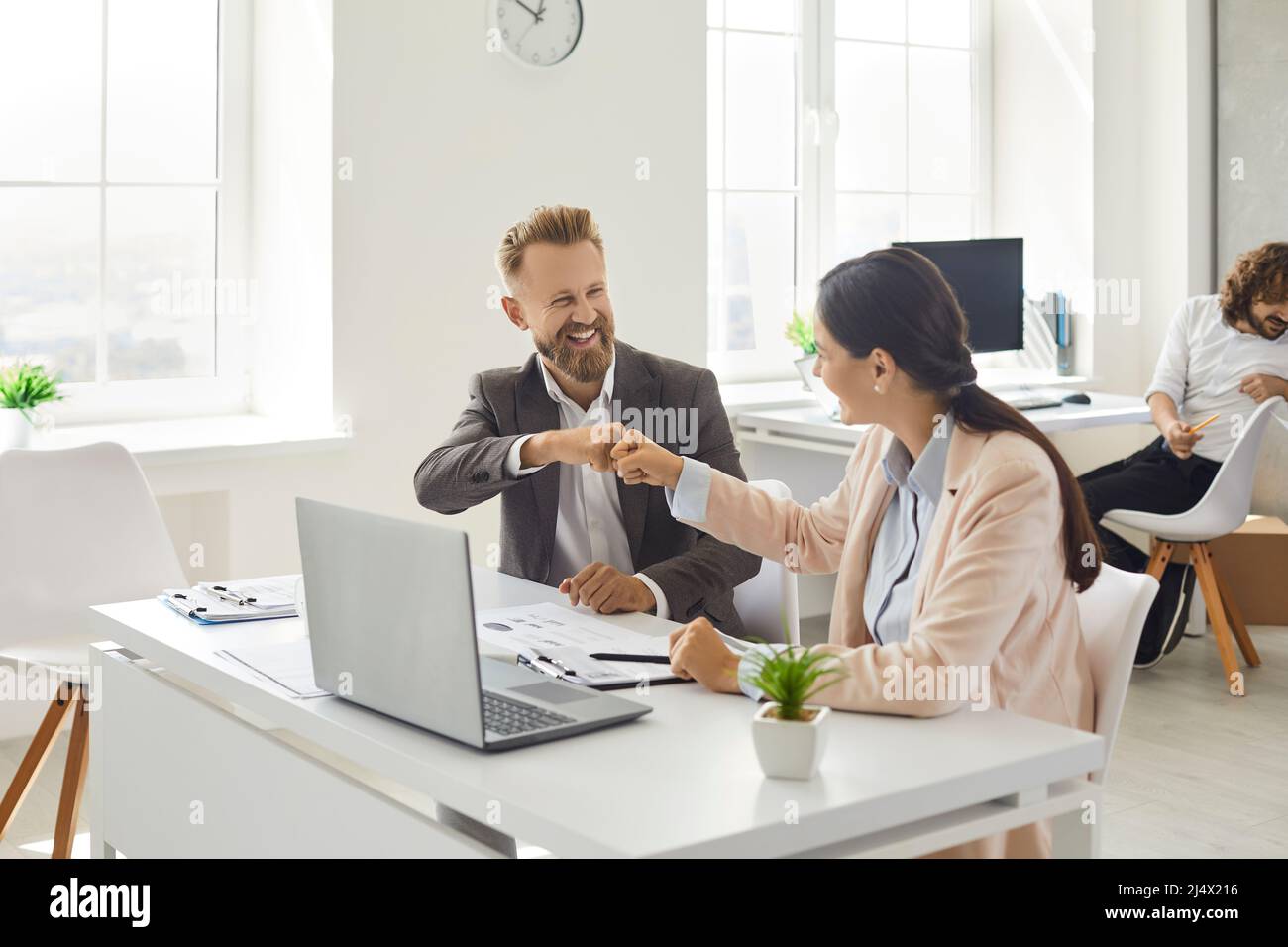Two happy young business people making a business deal, fist bumping ...