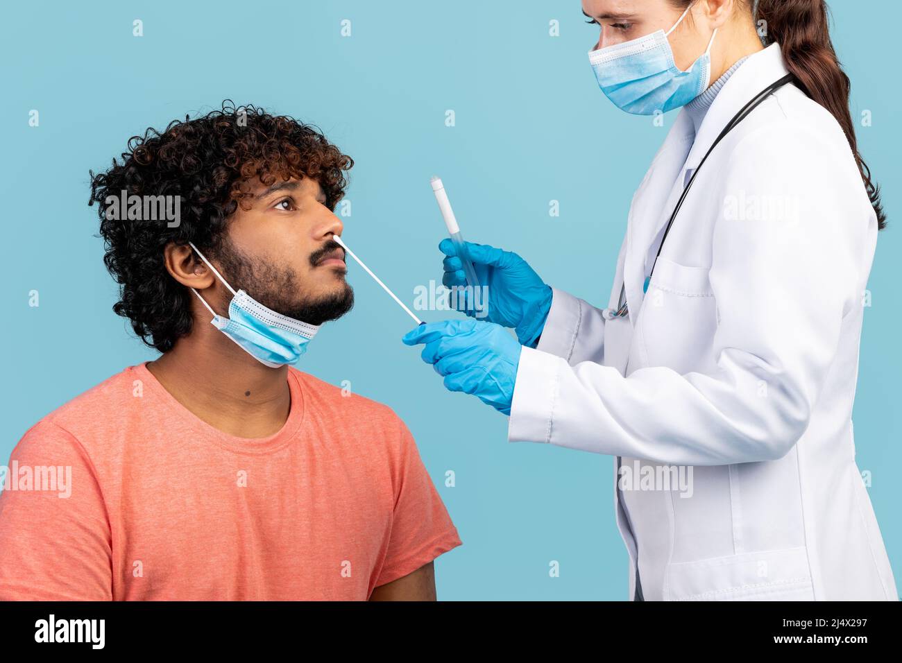 Female doctor taking nasal speciment from young indian man Stock Photo ...