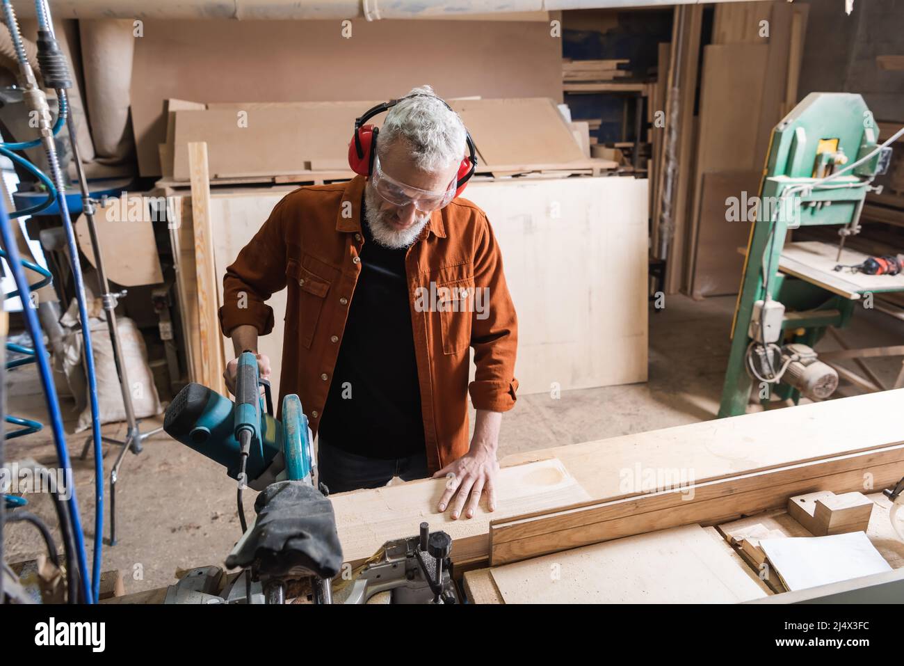 middle aged woodworker cutting timber in carpentry studio Stock Photo ...