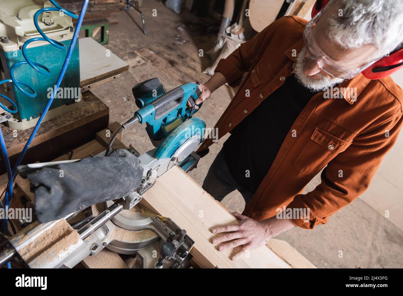 high angle view of mature carpenter cutting board with miter saw Stock ...