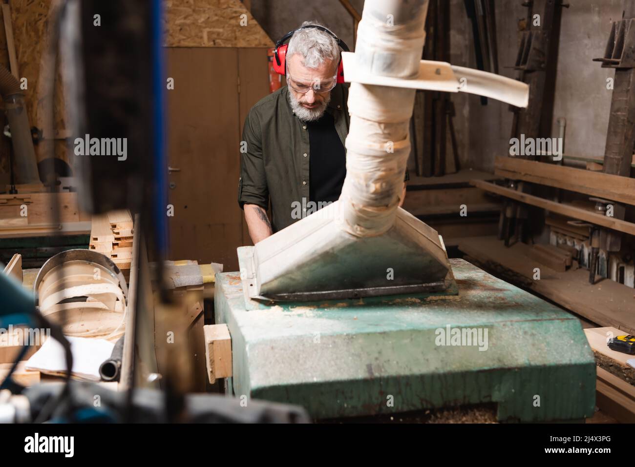 bearded carpenter working near ventilation hood on blurred foreground ...