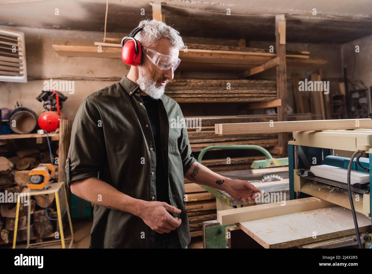 grey haired carpenter working near thickness planer in workshop Stock ...
