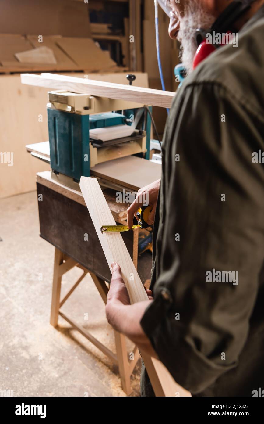 partial view of woodworker measuring plank near thickness planer Stock ...