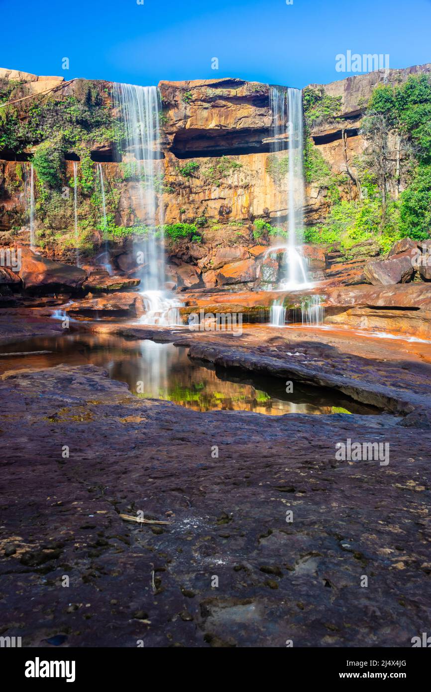 waterfall falling from mountain top with reflection and blue sky at ...