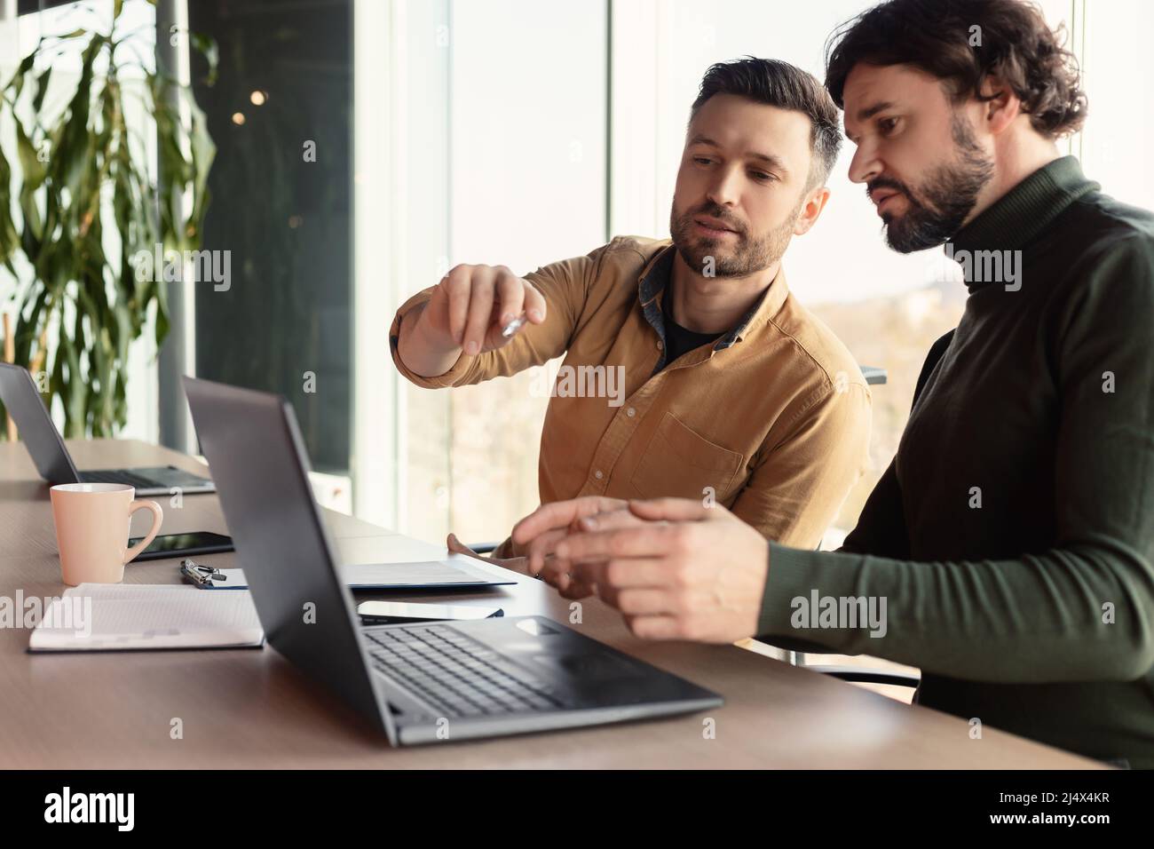 Serious employee speaking to his male colleague at company office ...