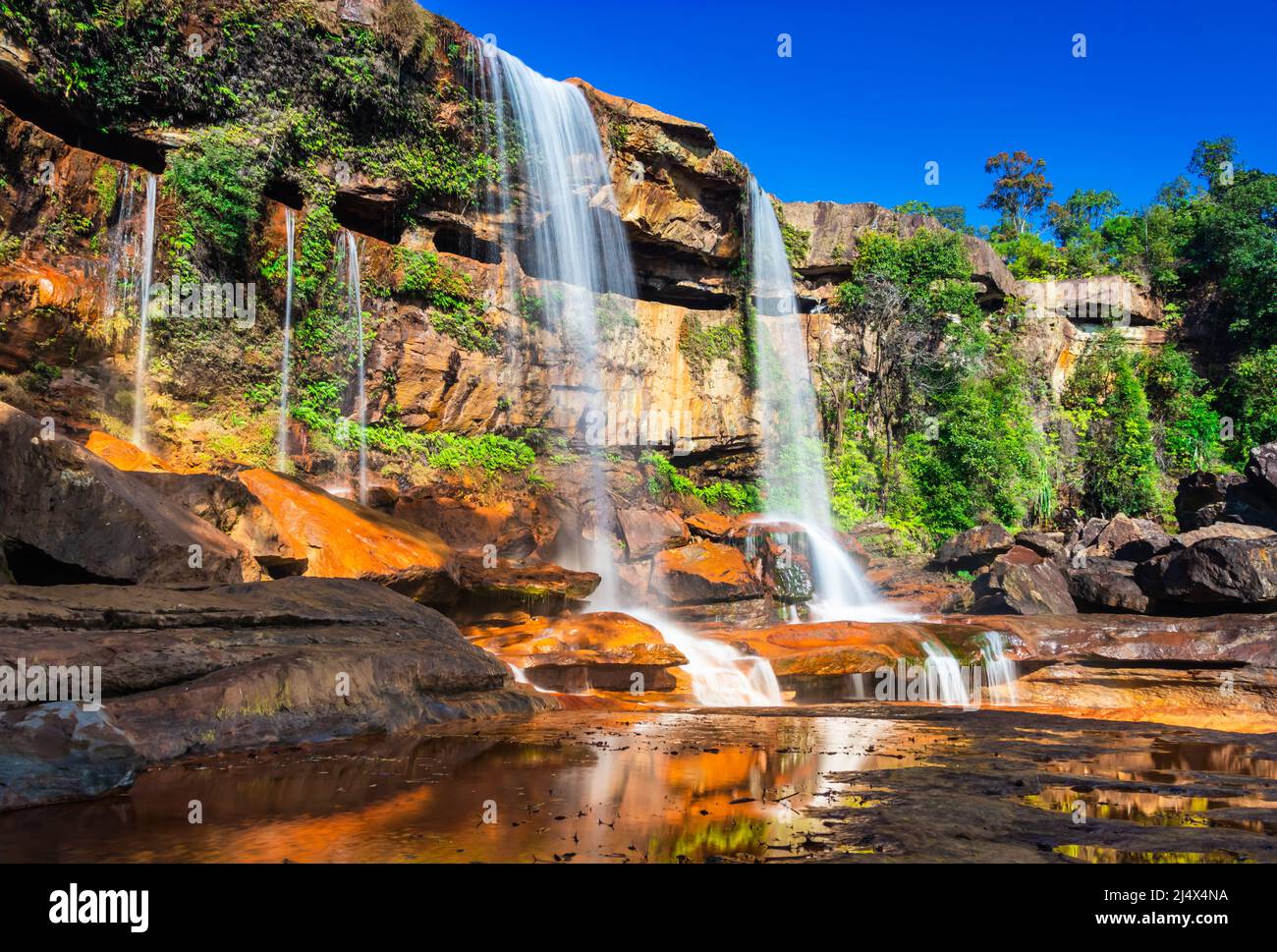 waterfall falling from mountain top with reflection and blue sky at ...
