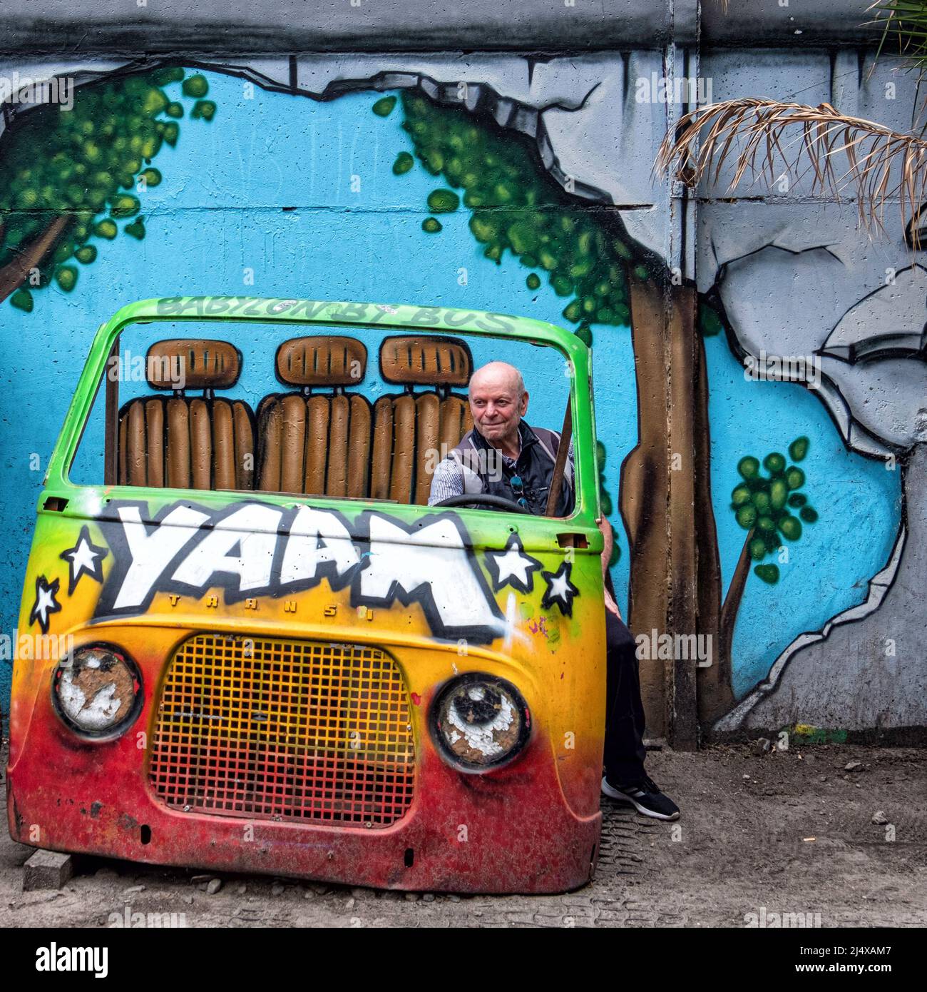 Elderly man sits in old painted car at YAAM Young African Art Market at ...