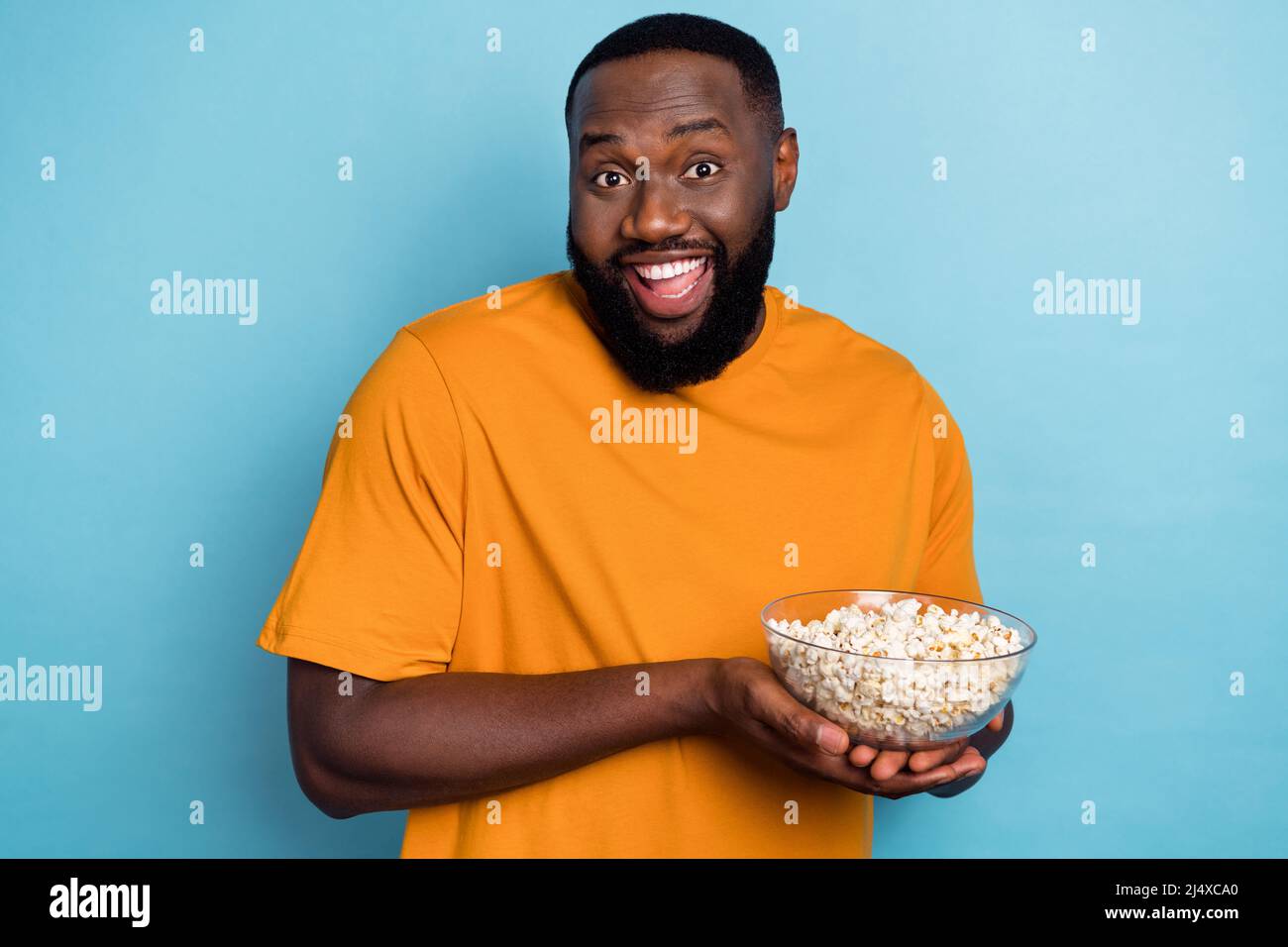 Portrait of attractive cheerful guy eating popcorn watching tv series ...
