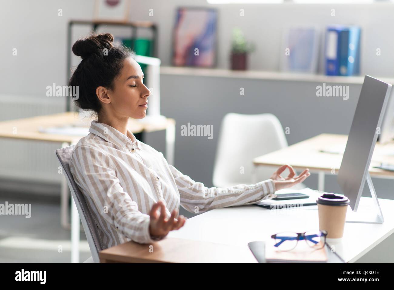 Coping with stress at work. Young latin office worker meditating at ...