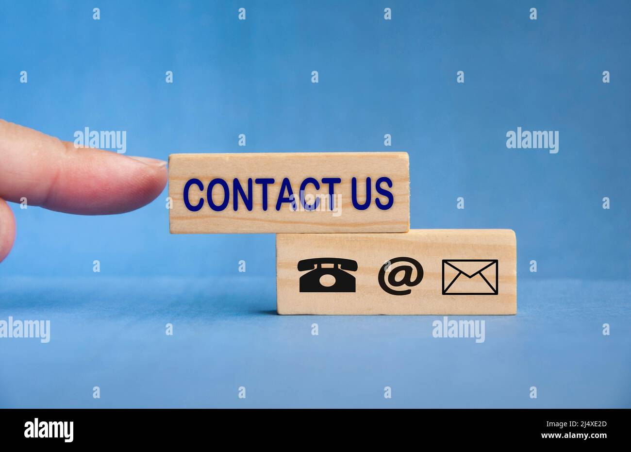 Finger pointing contact us text on wooden block with communication icon ...