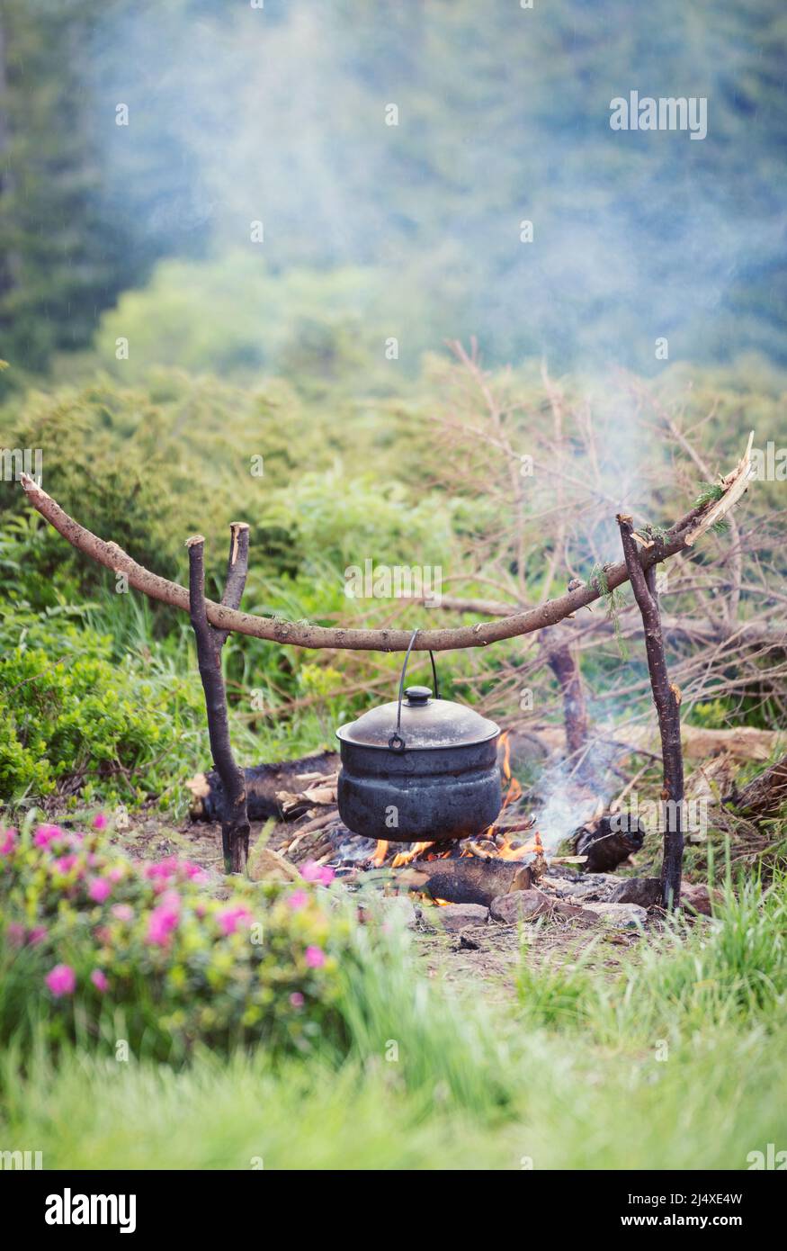 Cooking in field conditions, boiling pot at the campfire on picnic ...