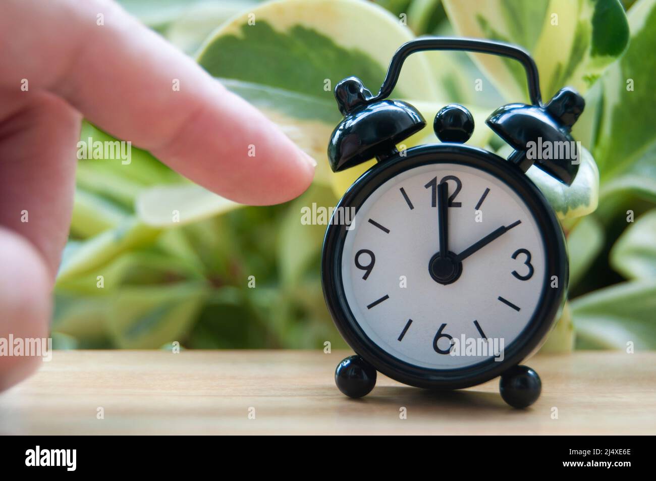 Hand pointing alarm clock that points at 2 pm. Copy space Stock Photo ...