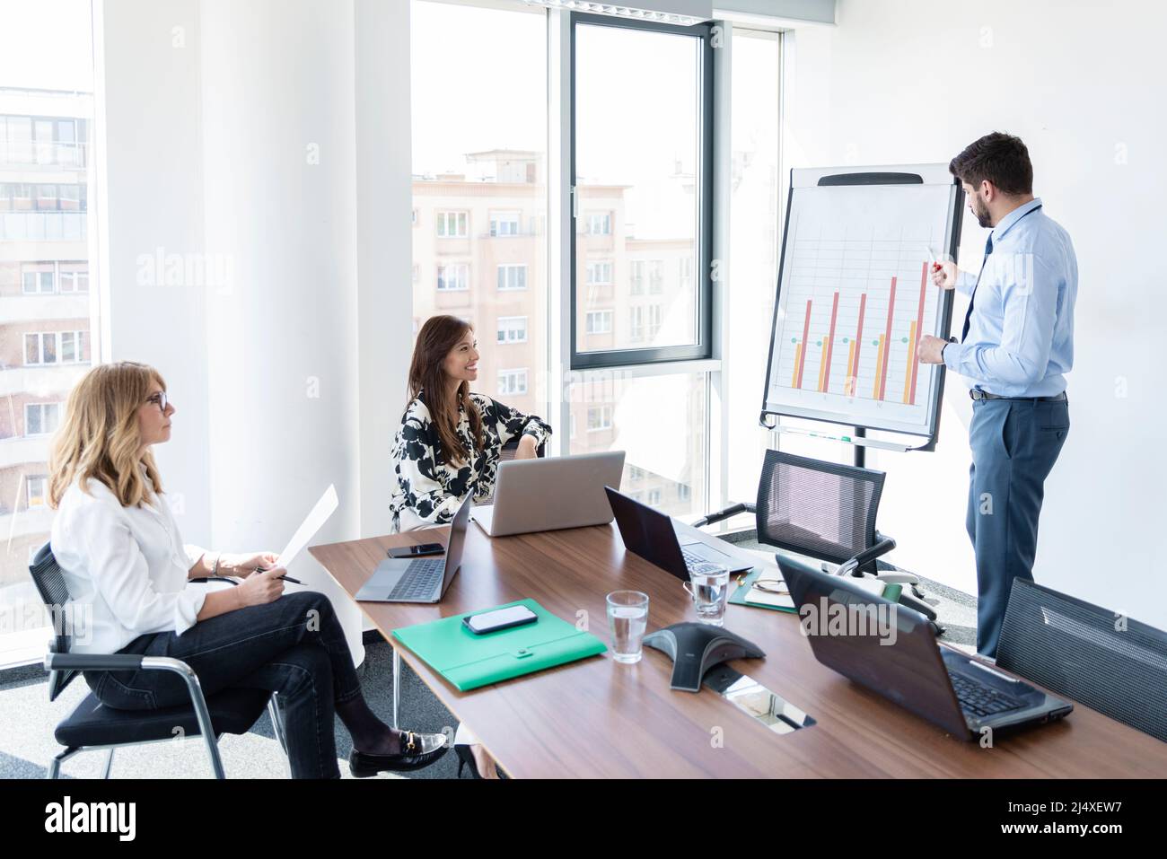 Businessman pointing at a chart on a whiteboard during business meeting. Group of business ...