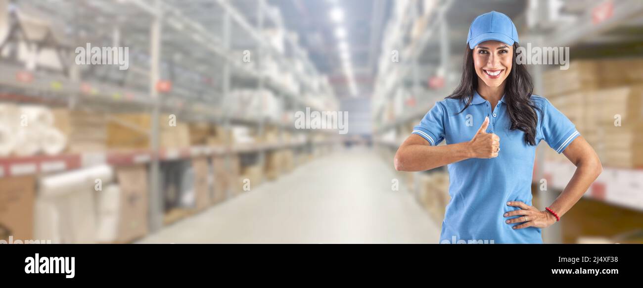 Young delivery woman in work clothes in front of a huge warehouse ...