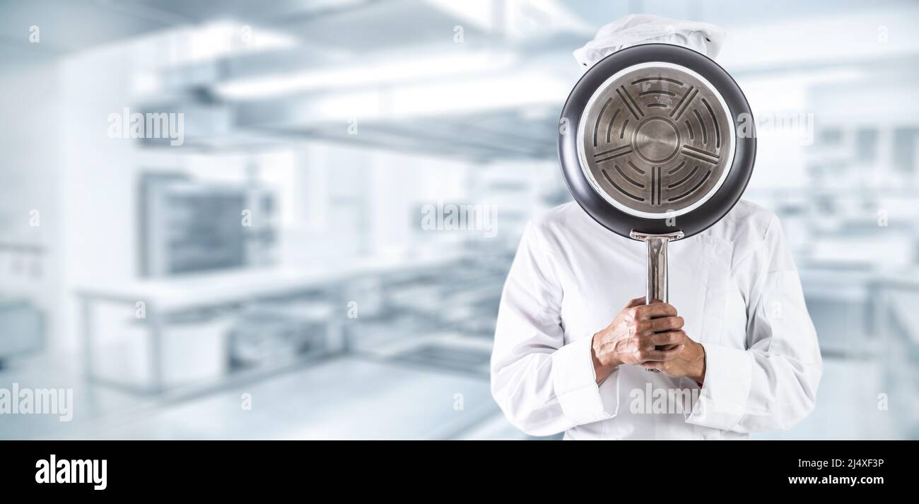 A chef in a restaurant kitchen with a frying pan covers his face Stock ...