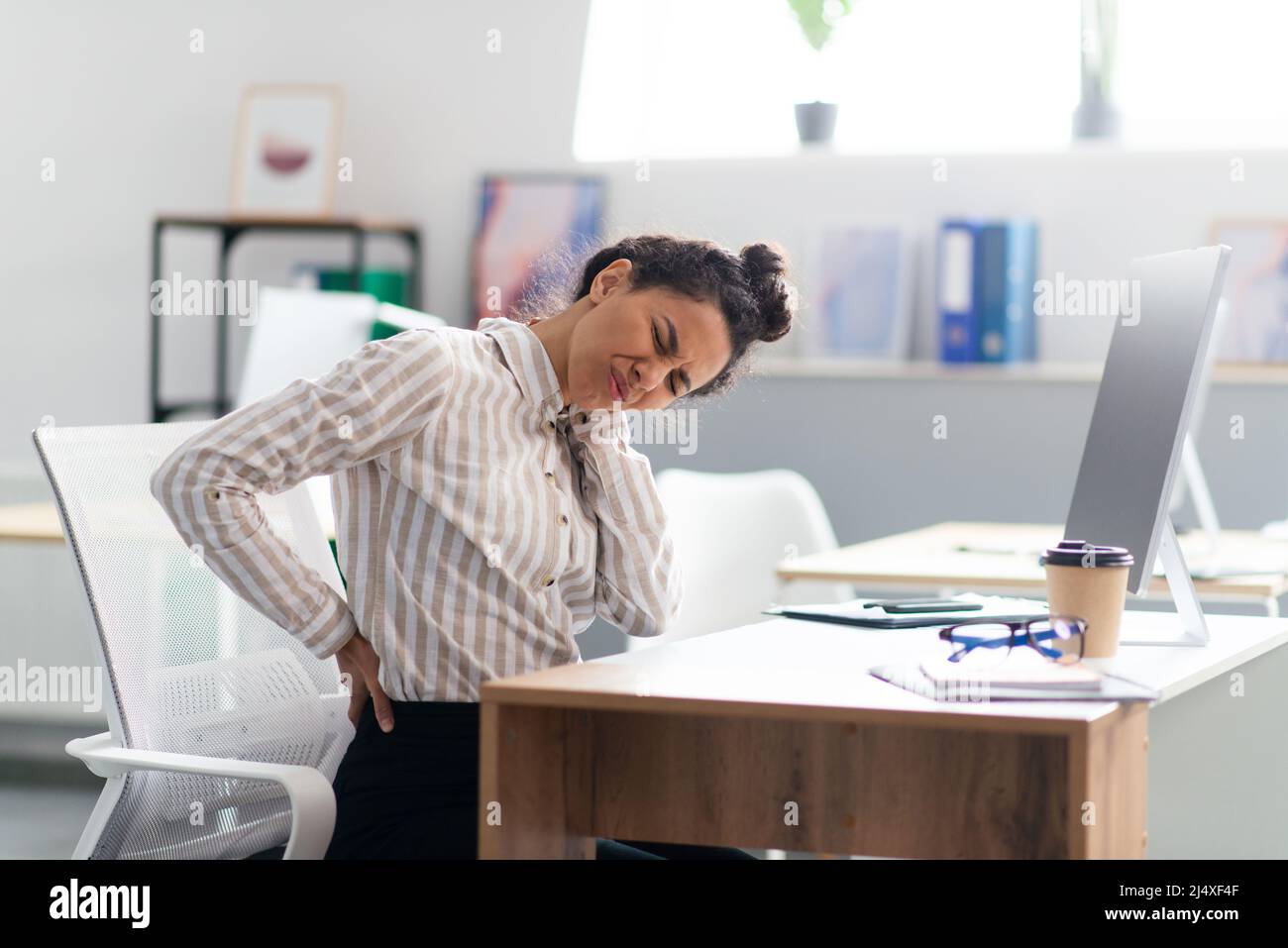 Tired businesswoman suffering from back and neck pain, muscle spasm at ...