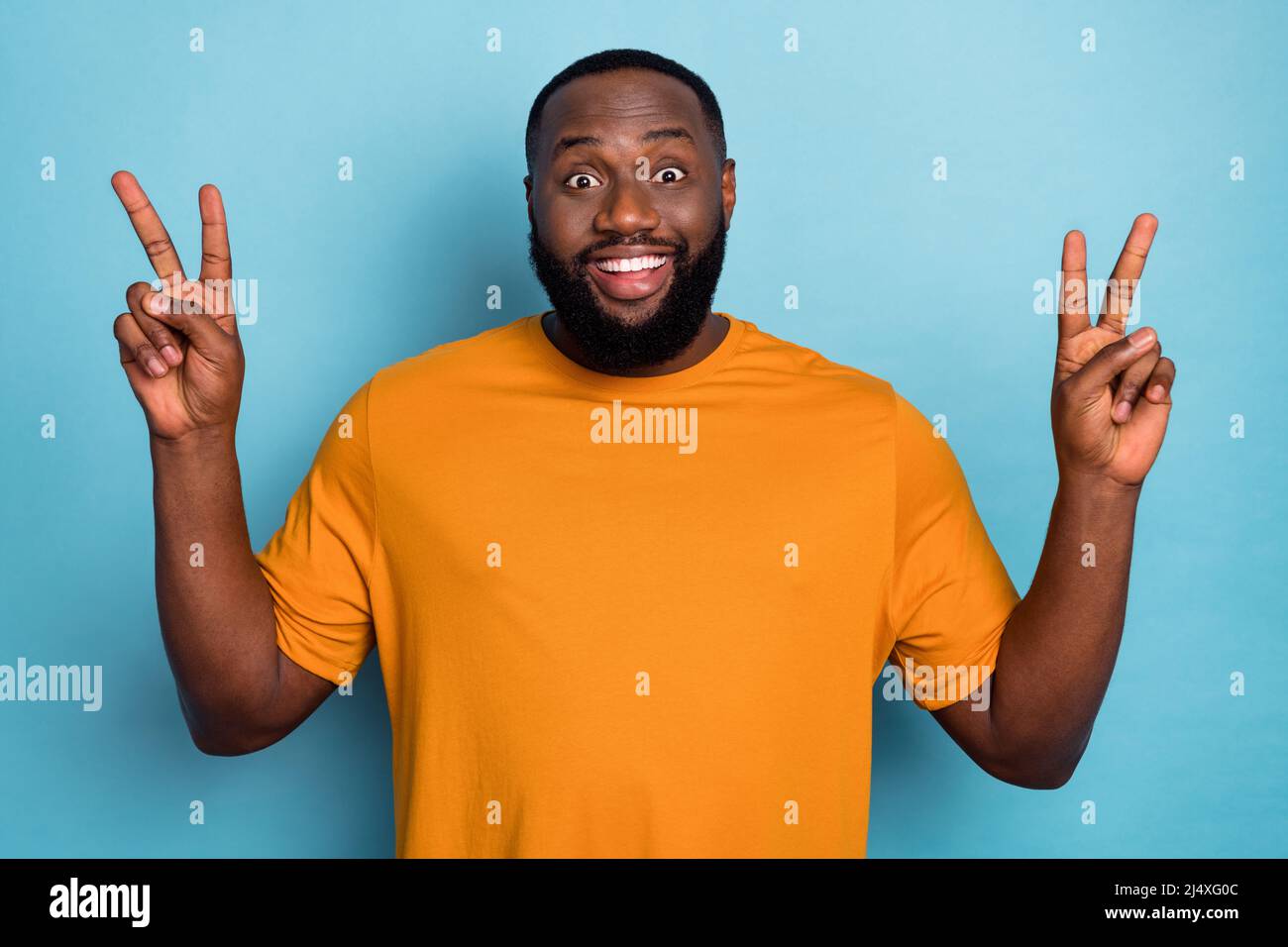 Photo of excited funky guy dressed orange t-shirt showing two v-signs ...
