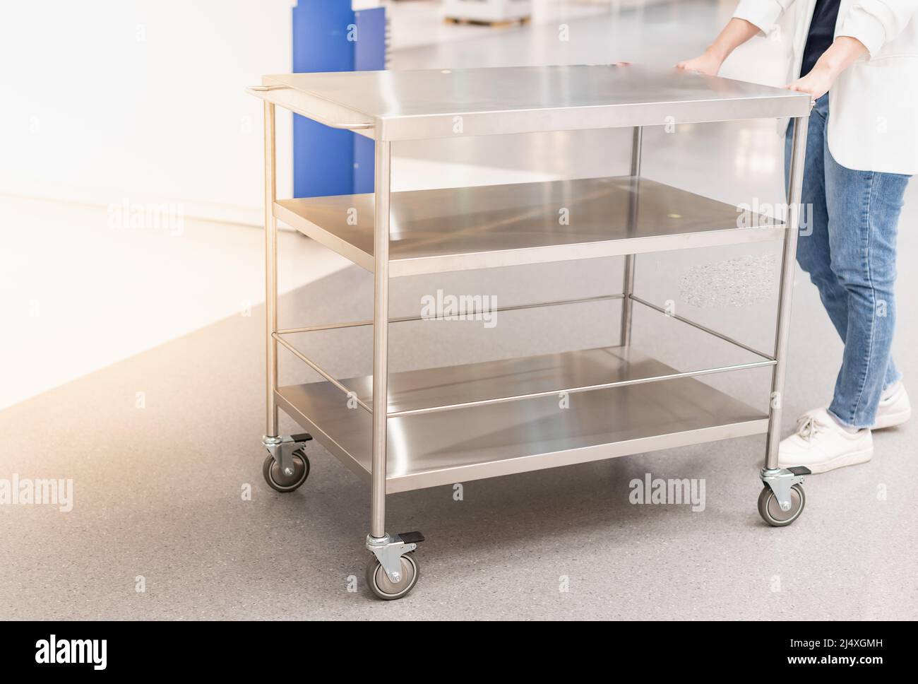 Female hand pushing the stainless steel food trolley cart to move a lot ...