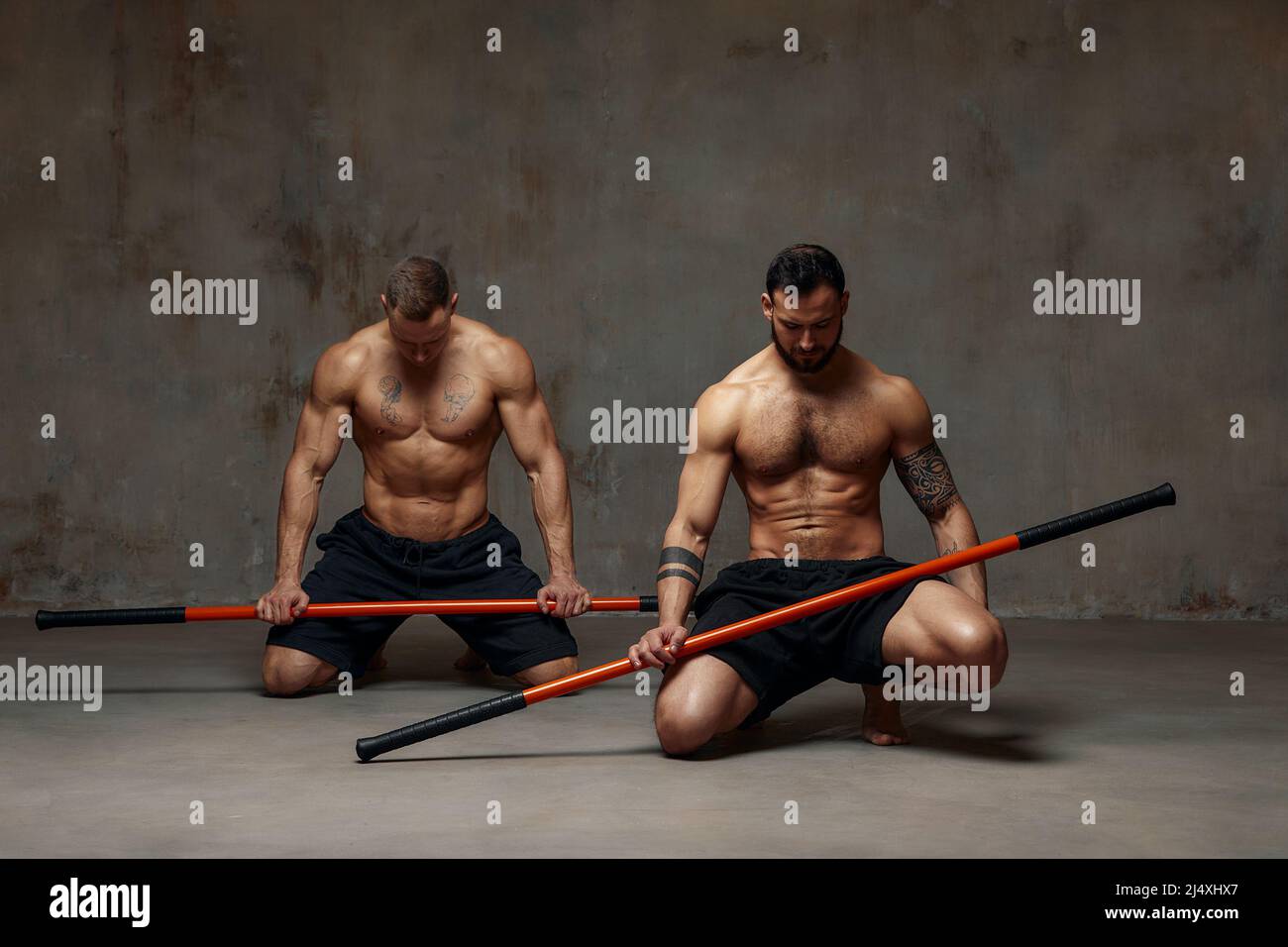 Two men aikido fighters with wooden fight stick posing in studio, fight ...