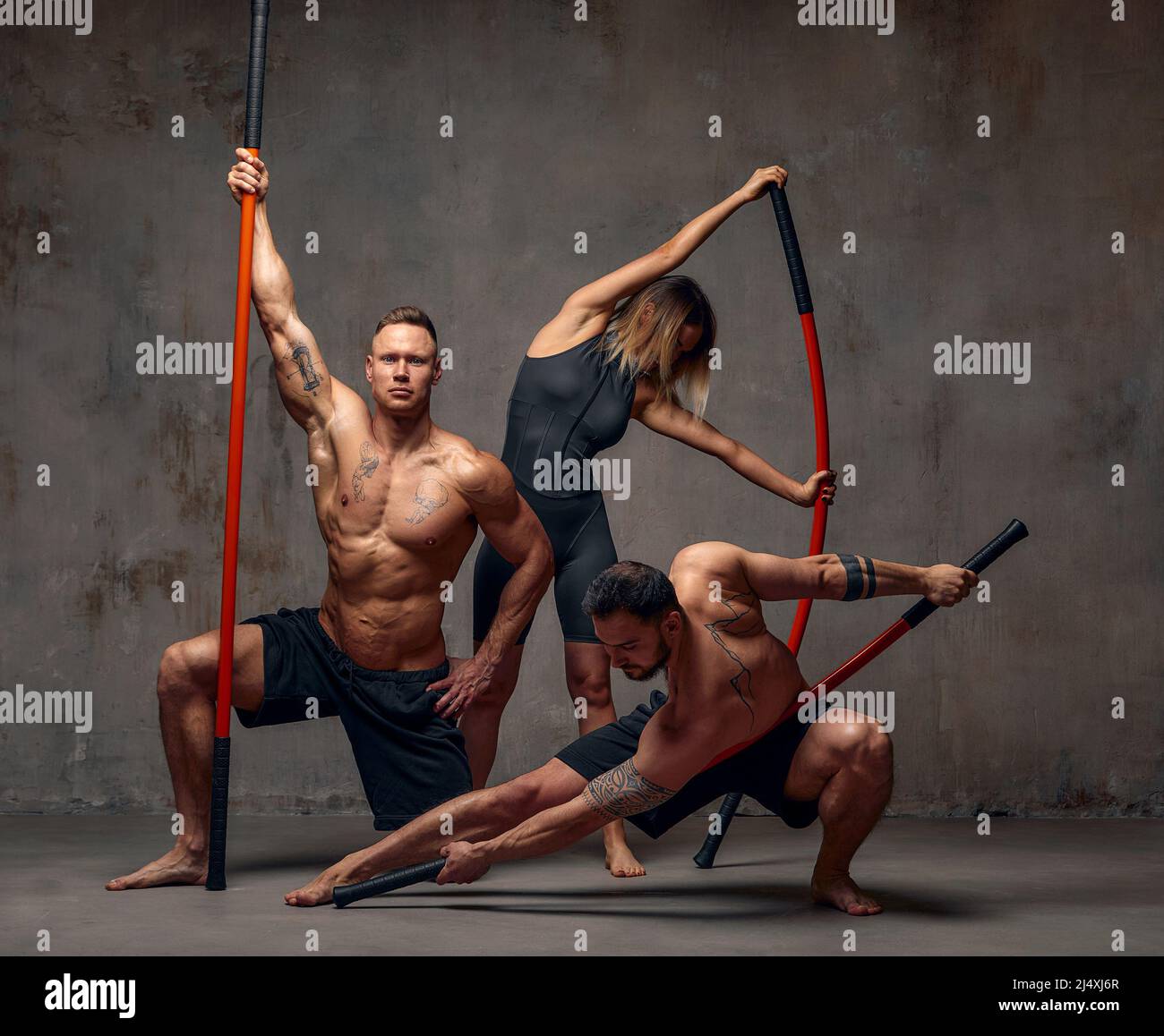 Two men and woman aikido fighters with wooden fight stick posing in ...