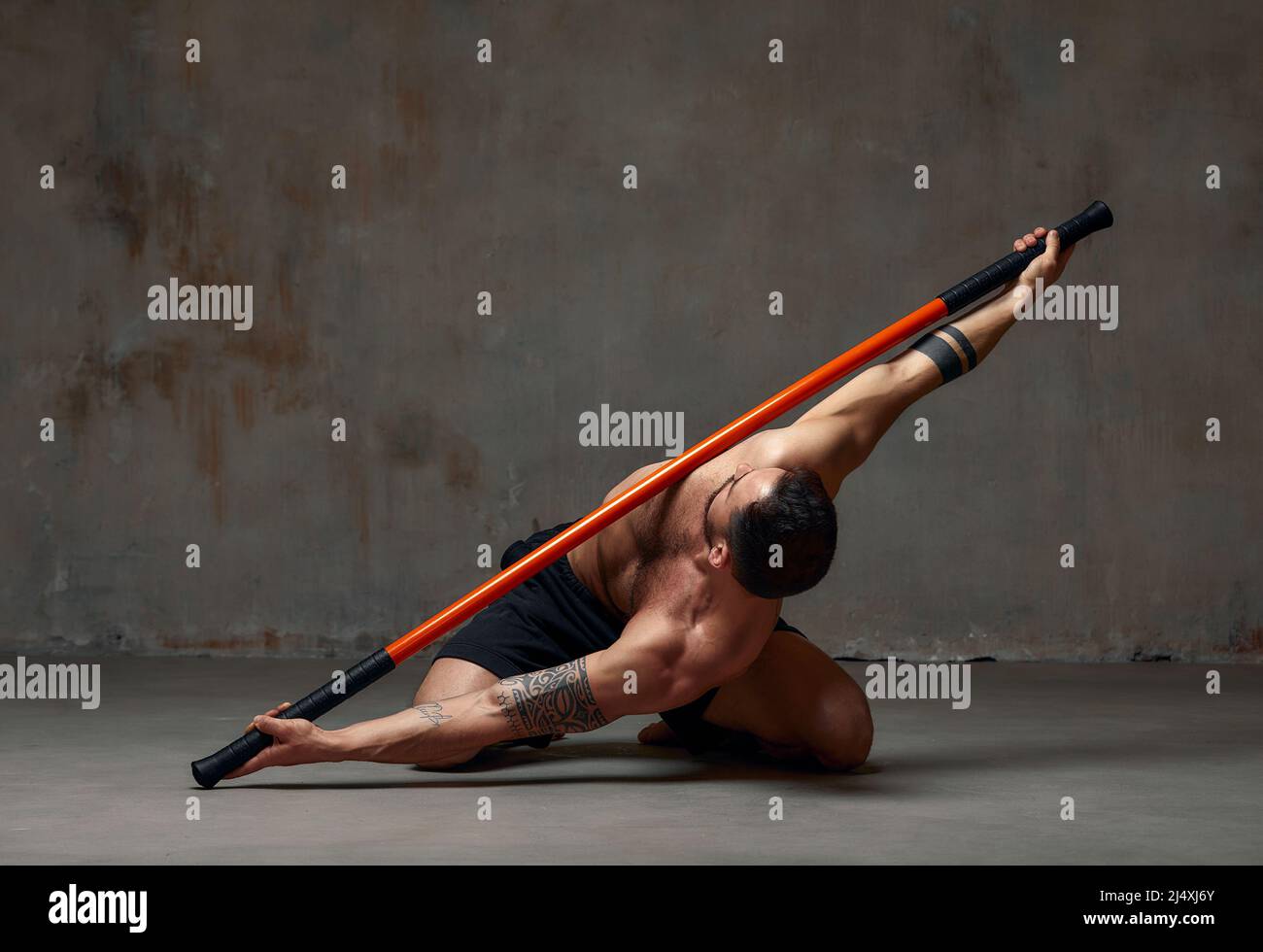 A ninja man holds on to a fighting stick and attacks close-up on gray ...