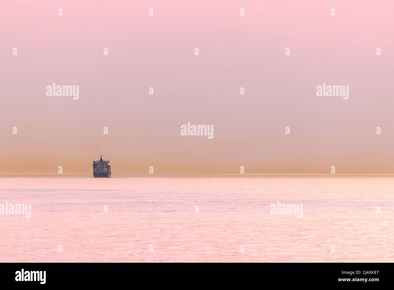 Container ship and line of haze in pink afterglow Stock Photo - Alamy
