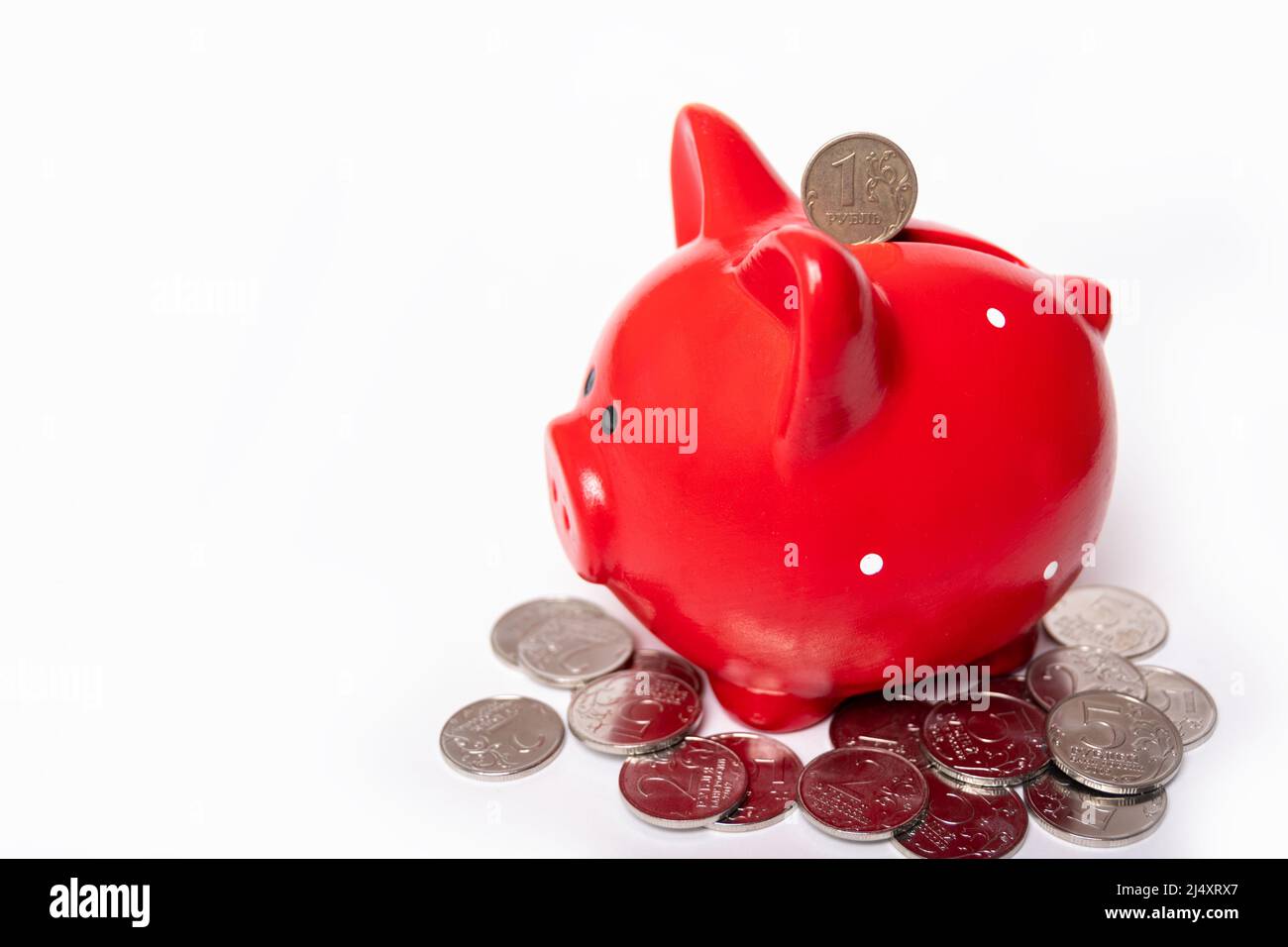 Russian coin 1 ruble in a hole in a red piggy bank on a white ...